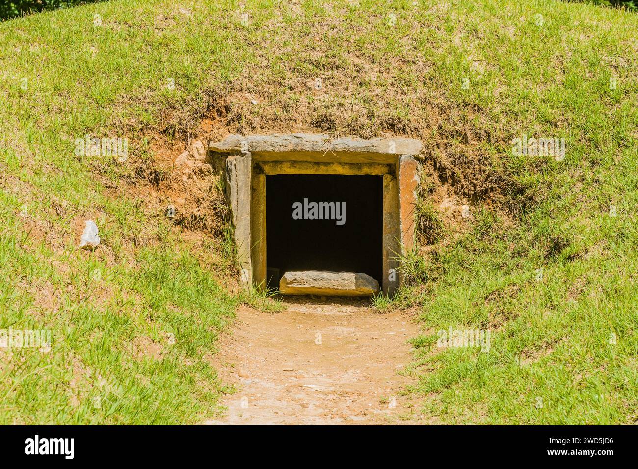 Unmarked mound tomb with dirt path leading to concrete opening on dry ...