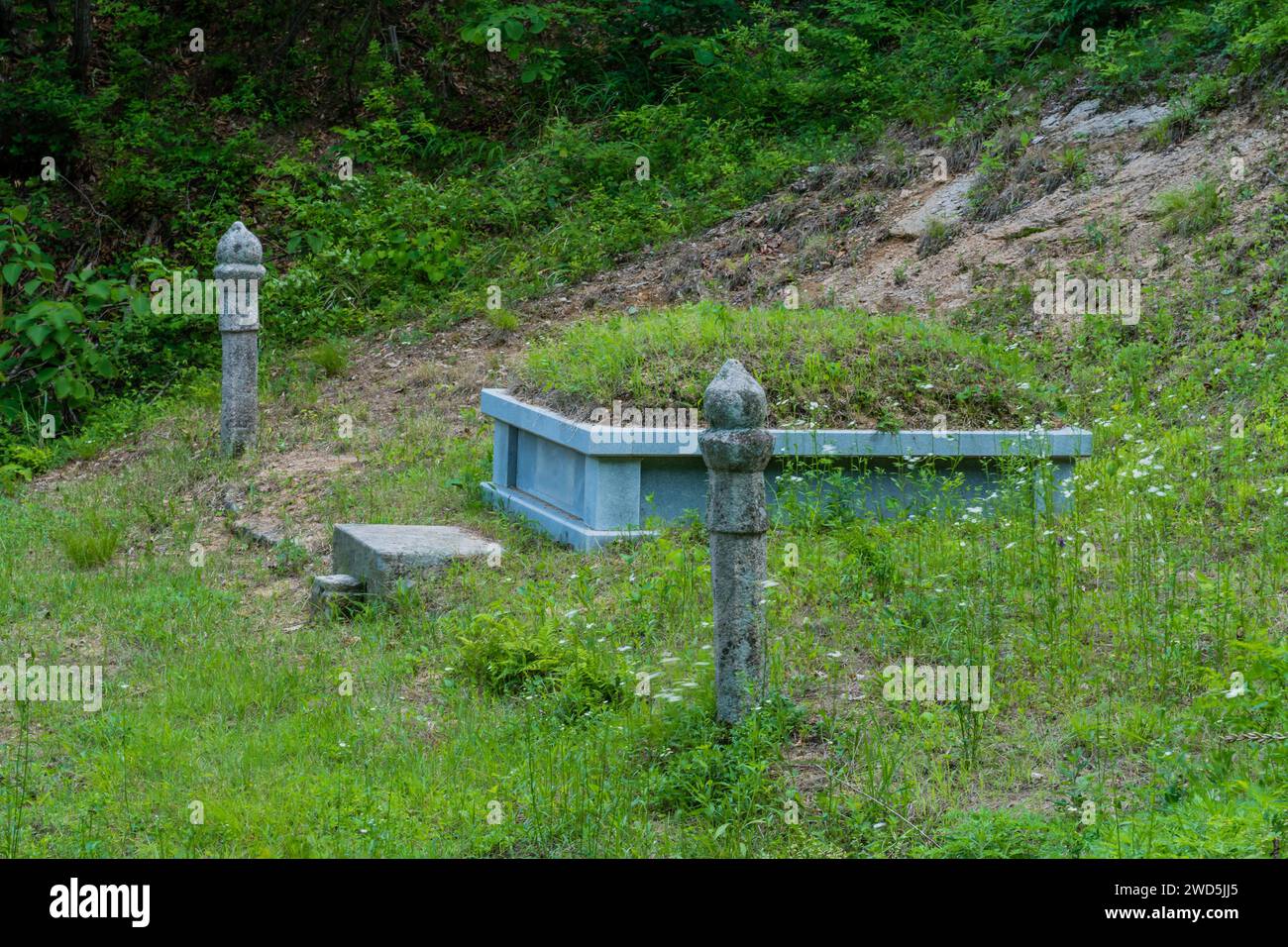 Unmarked burial mound in concrete casing on grass covered mountainside ...