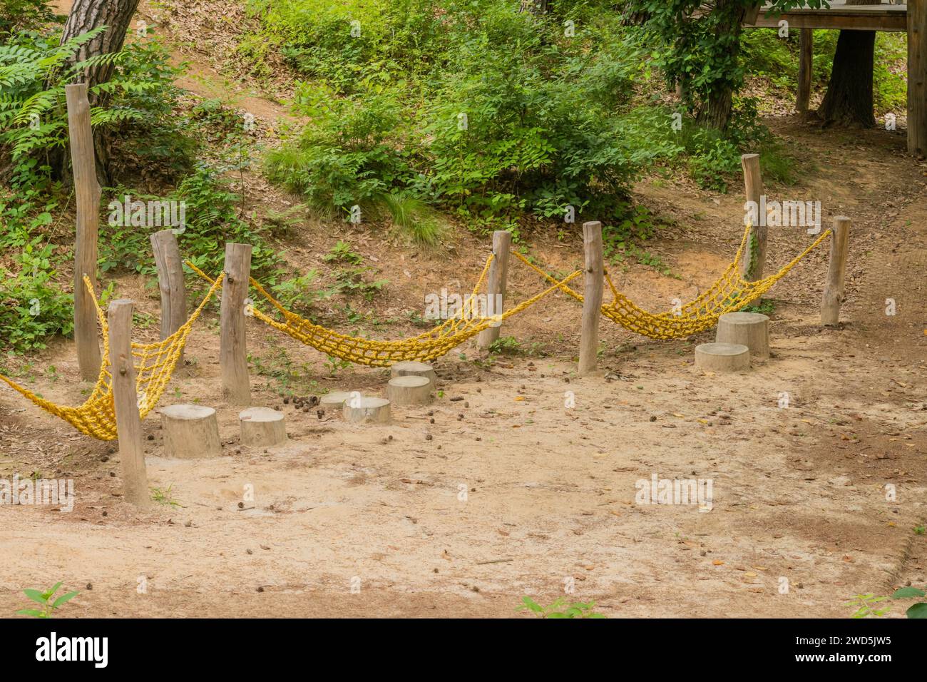 Yellow rope bridge hanging between wood posts, part of exercise and ...