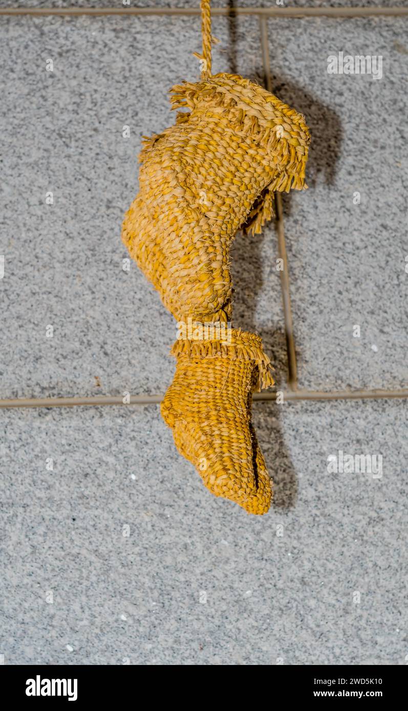 Two pair homemade wicker shoes hanging in front of concrete wall, South ...