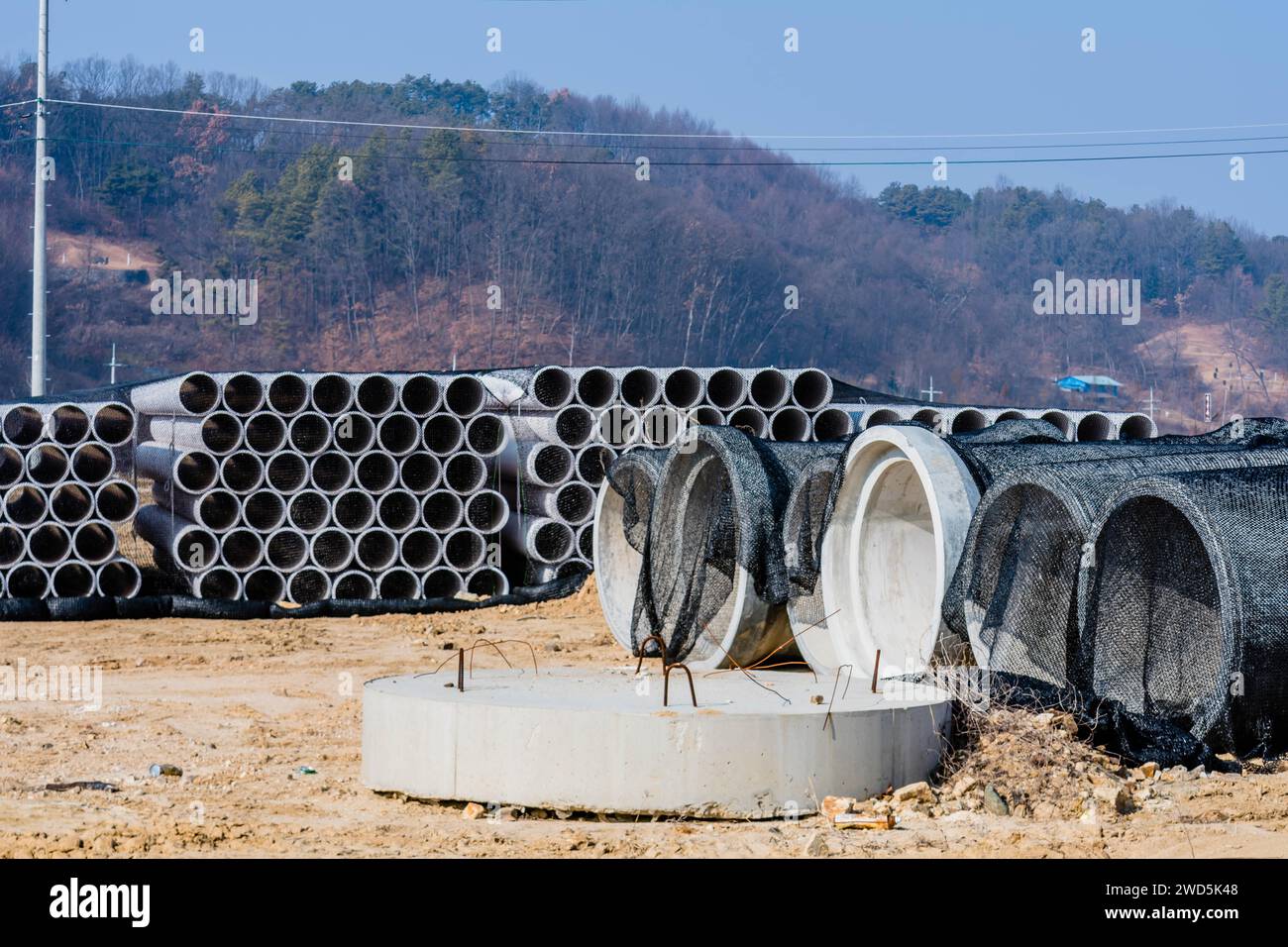 Large round concrete culverts in front of stacks of corrugated pipes ...