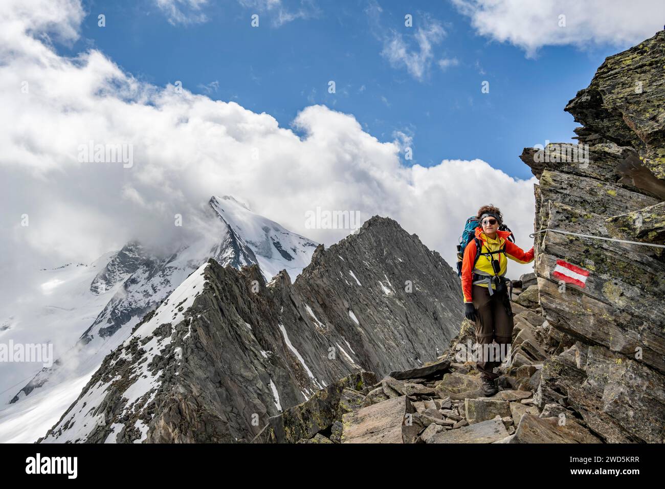 Mountaineer on a rocky path with safety rope and mountain panorama ...