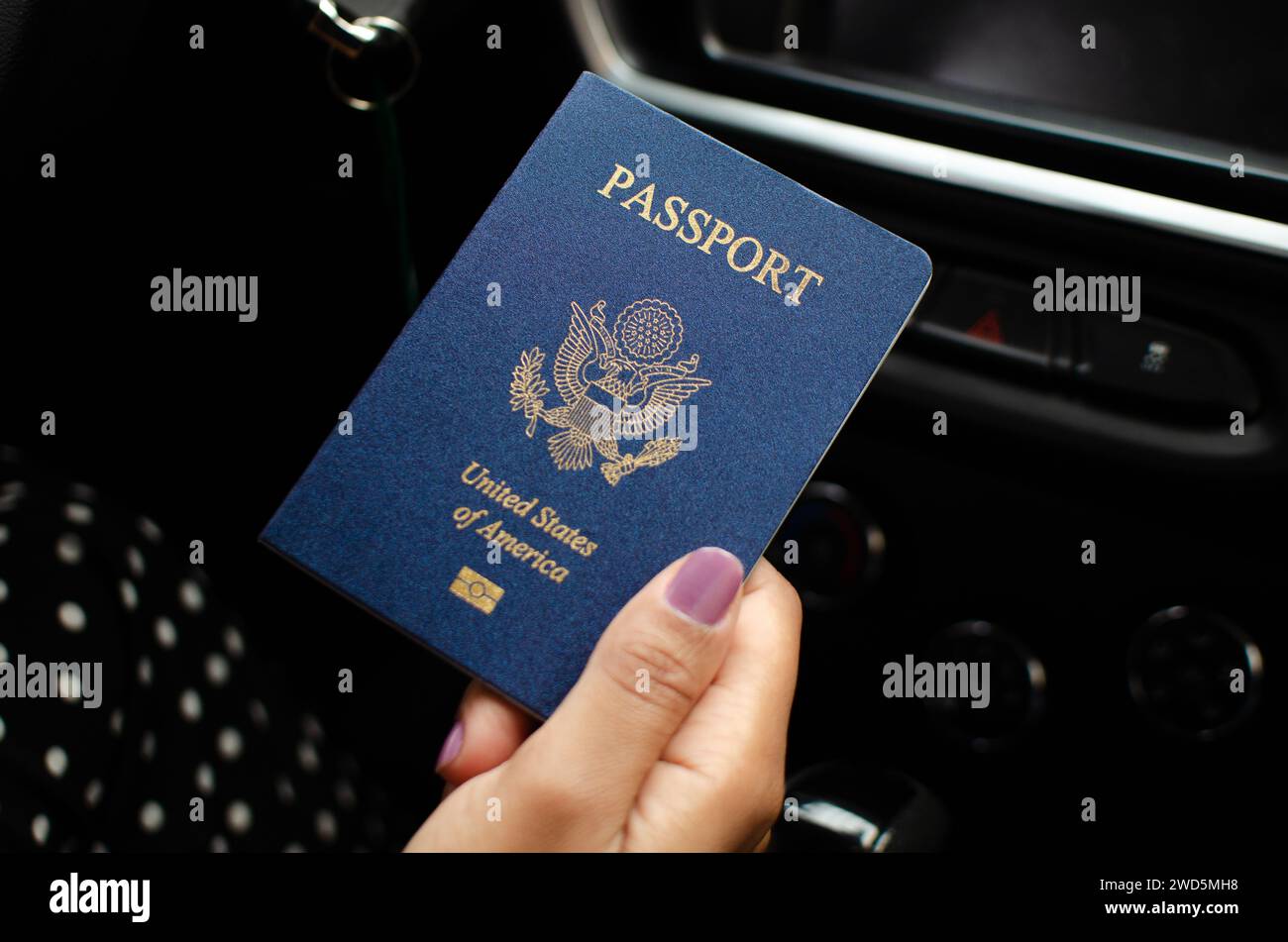 Close-up of an unidentified hand holding a closed American passport ...