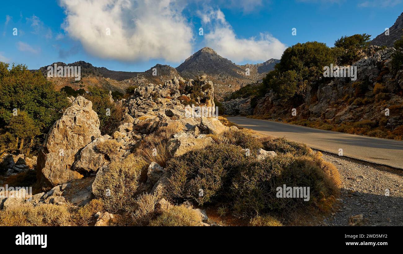 Rugged mountain road with lush vegetation and blue sky, Kallikratis ...