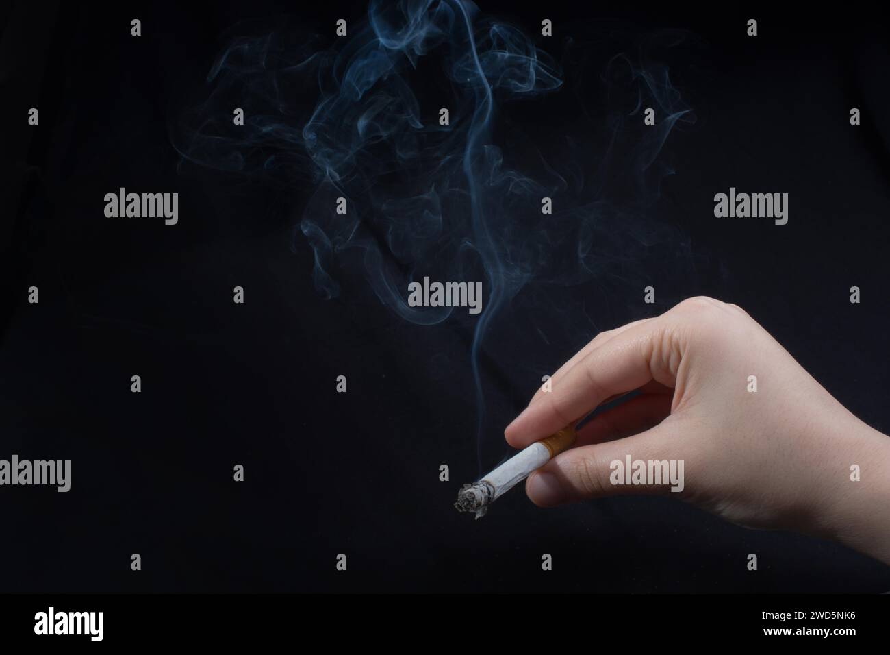 Hand is holding smoking cigarette with smoke around Stock Photo - Alamy