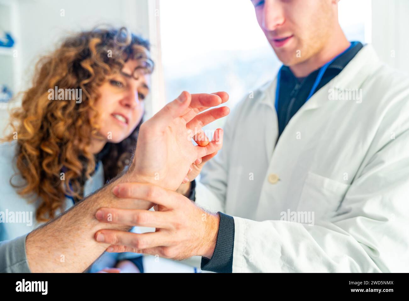 Traumatologist doctor examining the hand of a patient next to a nurse ...