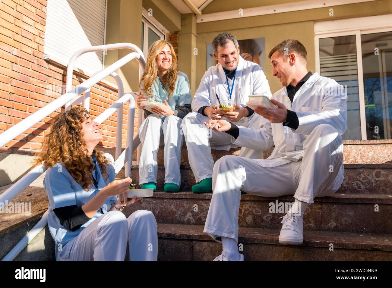 Medical coworkers smiling and chatting during lunch time sitting on ...