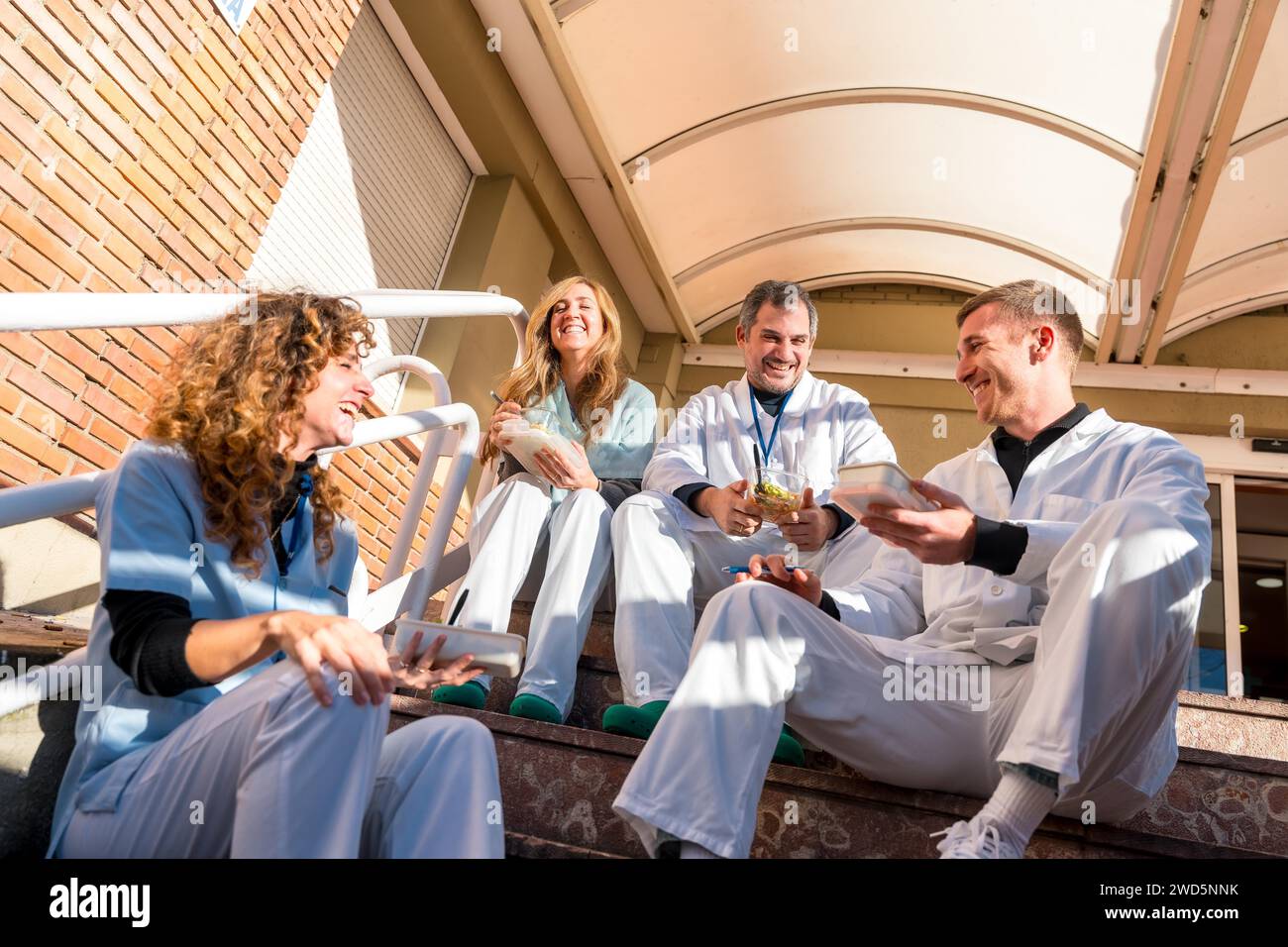 Happy doctors and nurses sharing lunch time outside the hospital in a ...