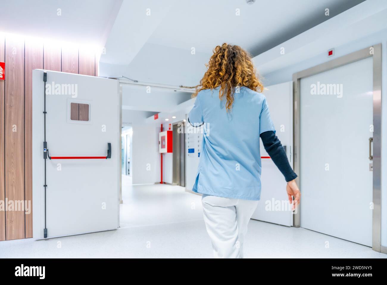Rear view of a nurse in a rush along the emergency area of an hospital ...