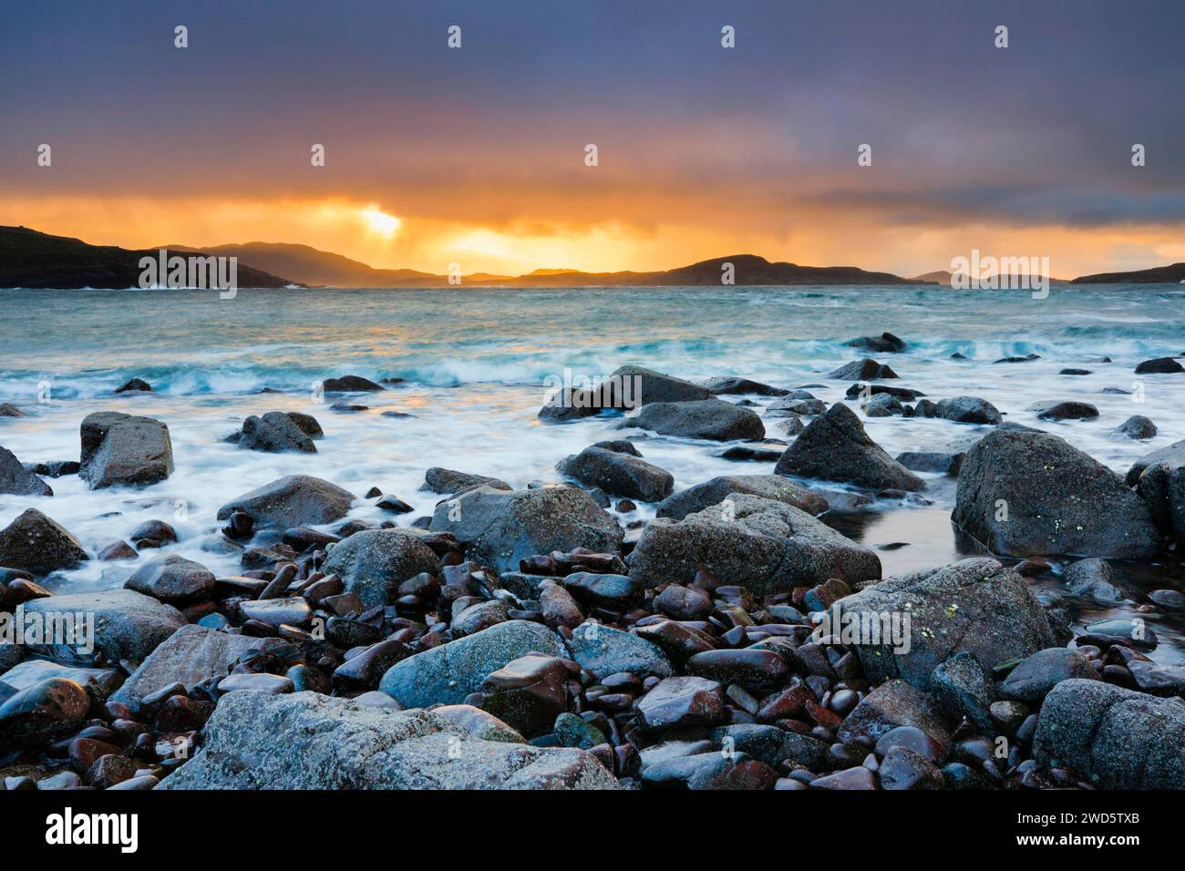 Atmospheric coloured cloudy sky at sunrise on a rocky beach near Reiff ...