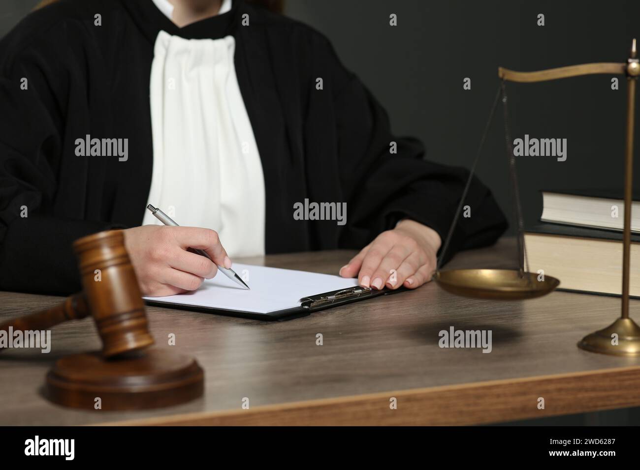 Judge with pen and clipboard working at wooden table in courtroom ...