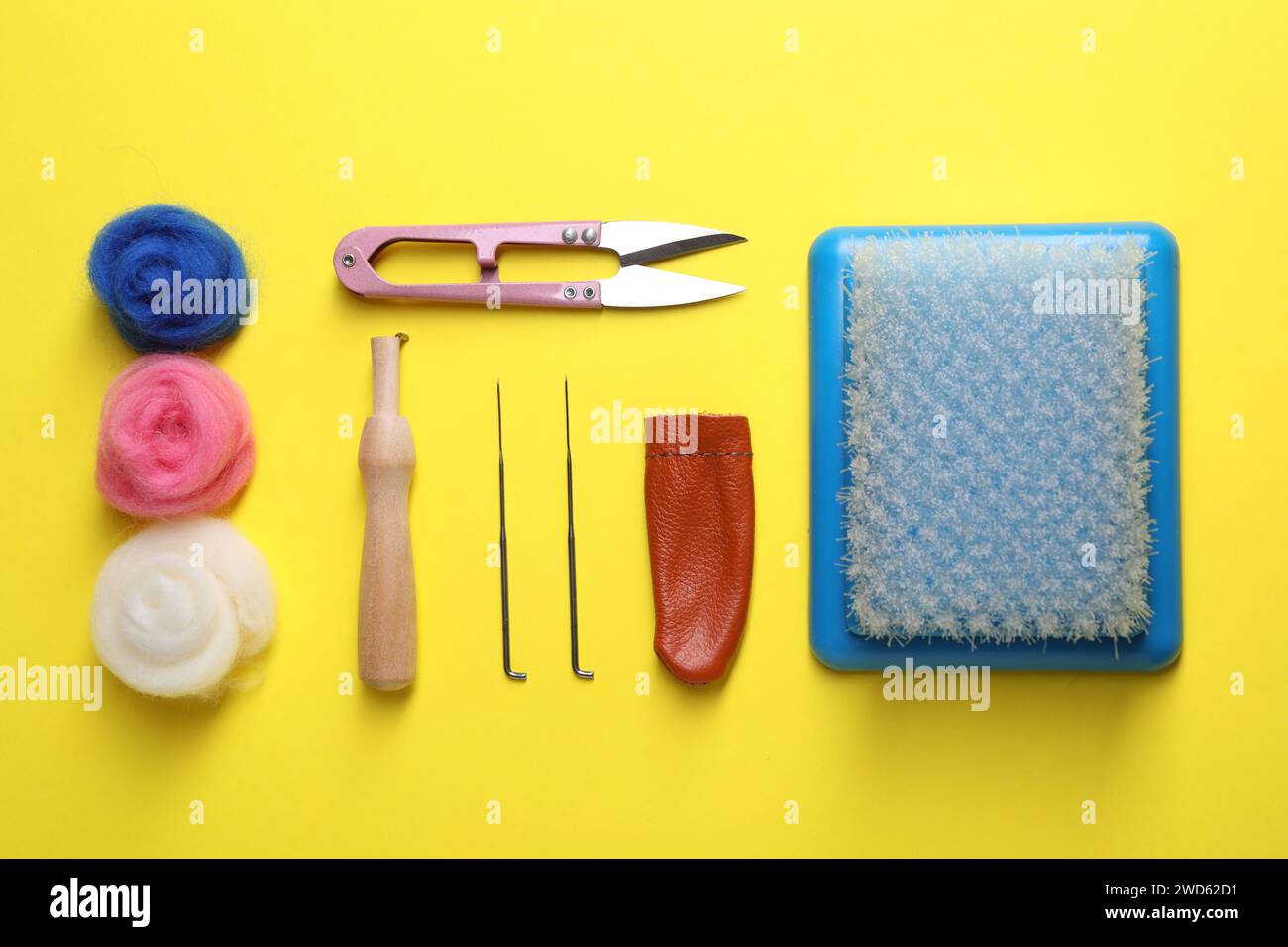 Flat lay composition with wool and needle felting tools on yellow ...