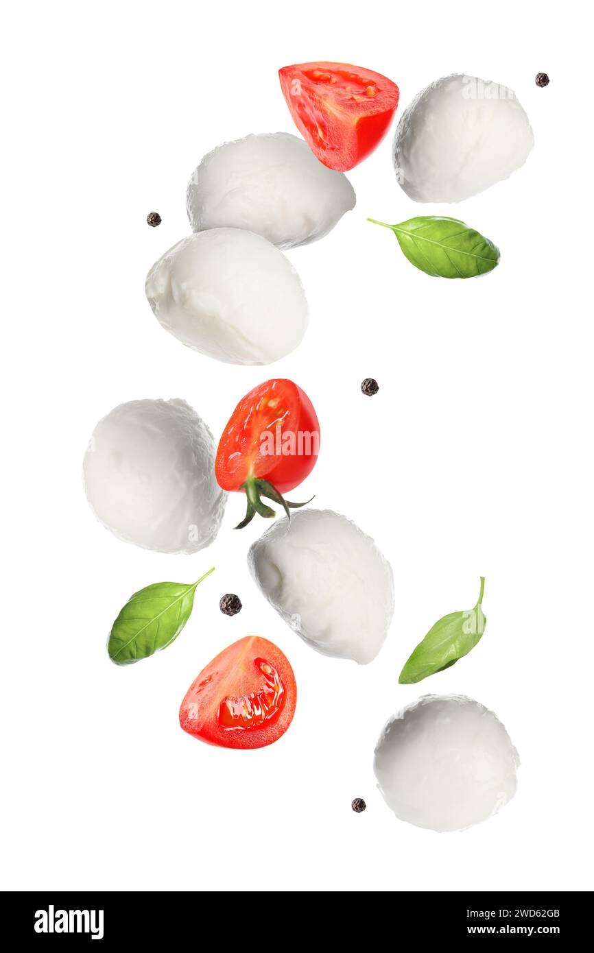 Mozzarella balls, cut tomatoes, basil leaves and peppercorns falling on ...