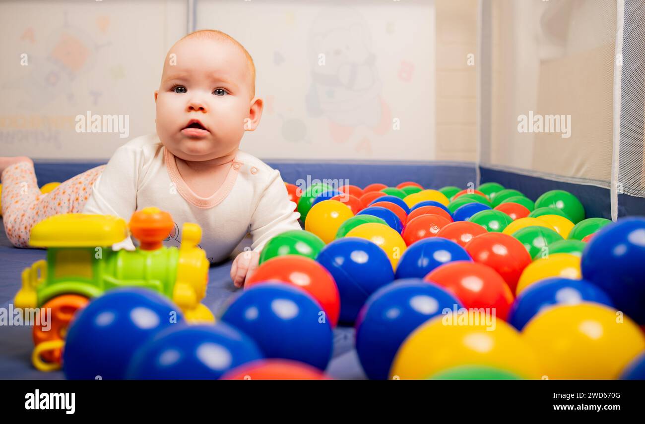 Cute baby girl playing with colorful balls in kindergarten Stock Photo ...