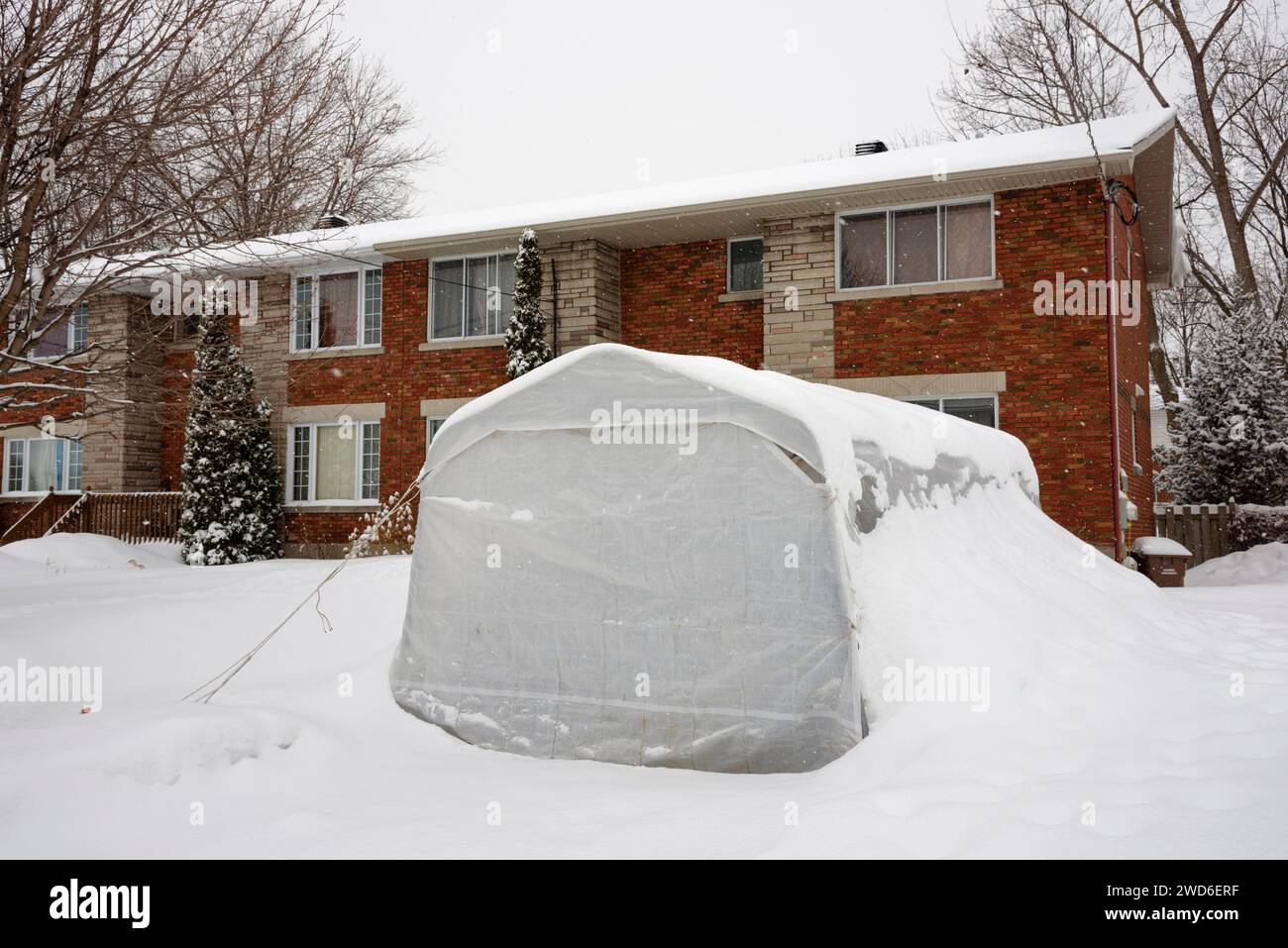 Temporary winter car shelter installed in the driveway of a duplex on a ...