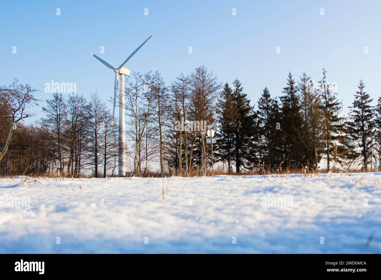 Wind turbine in forest on top of the hill with cloudy sky in background ...