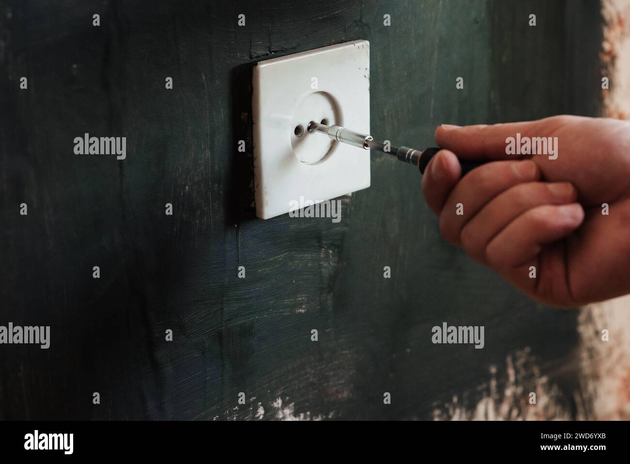 male electrician changes an old electrical outlet by unscrewing the ...