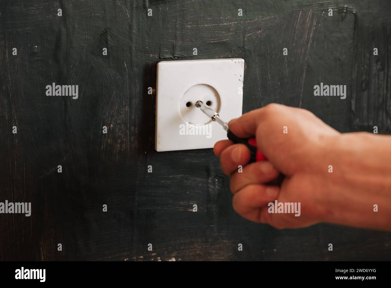 male electrician changes an old electrical outlet by unscrewing the ...