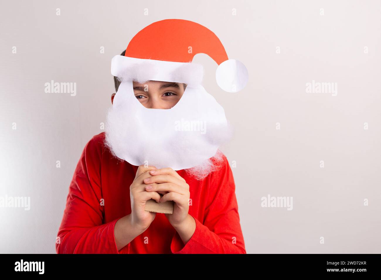 a boy wearing a paper craft santa hat and beard, disguise New Year mask ...