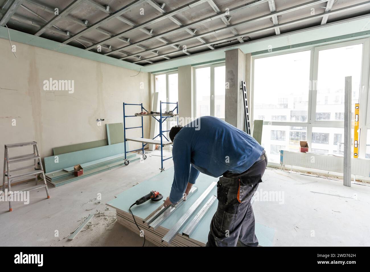 Construction worker assemble a suspended ceiling with drywall and ...