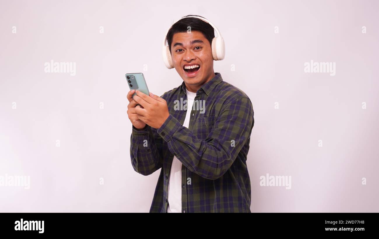 Asian young man listening music on smartphone using headphone wireless ...