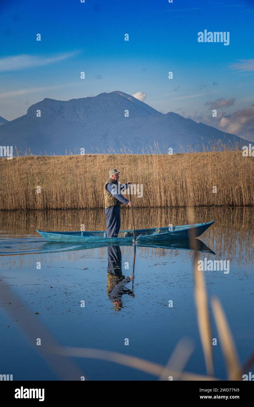 A man fishing in river, capturing fish with a net from the boat in ...