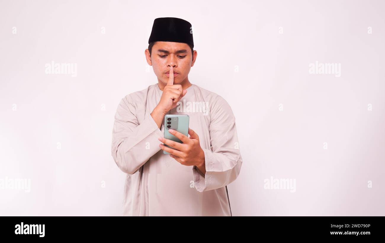 Asian muslim man holding smartphone and make a quite sign with his ...