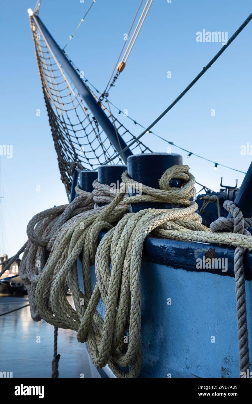Ship's ropes twisted around the iron bollards on the railing of a metal ...