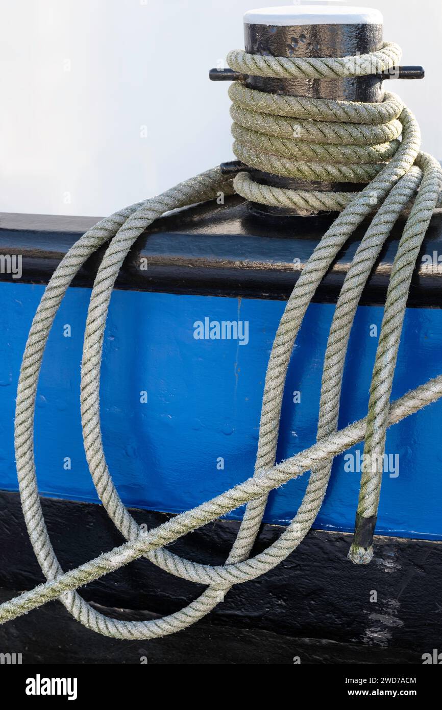 Ship's ropes twisted around the iron bollard on the railing of a metal ...