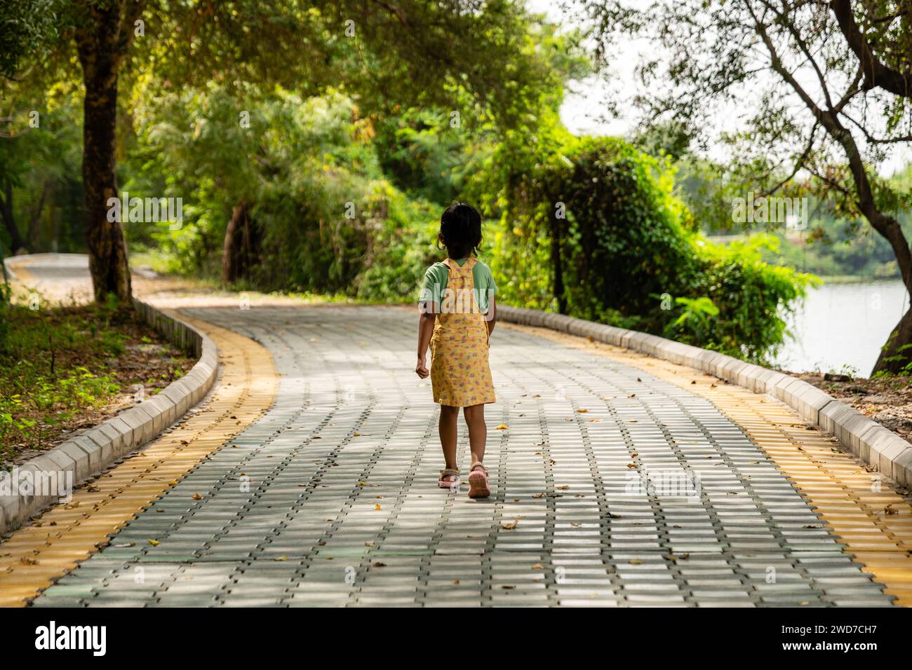 a young girl wanders thoughtfully along a secluded footpath. Tall trees ...
