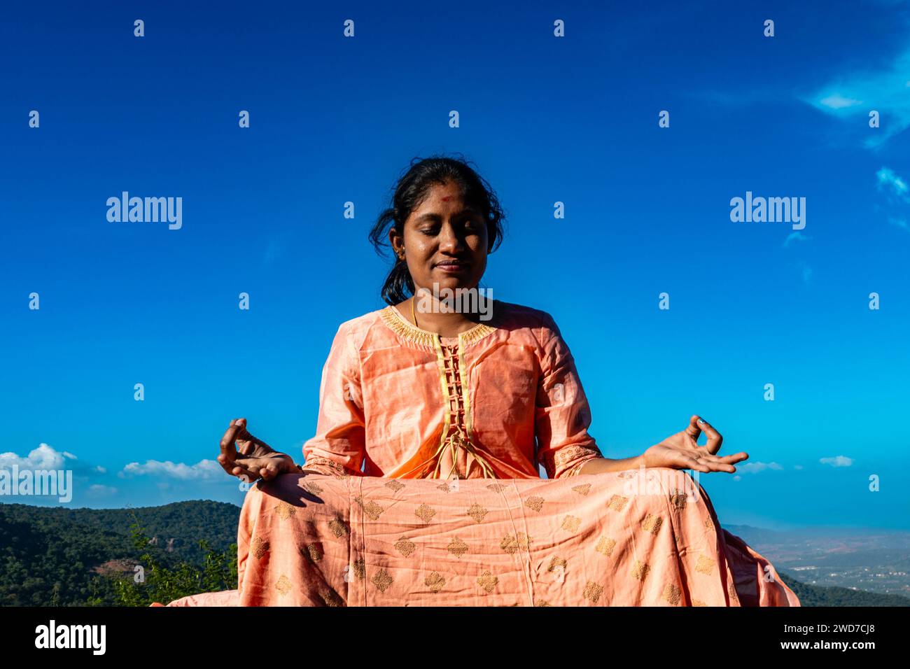 an Indian woman seeks solace and serenity through meditation atop a ...