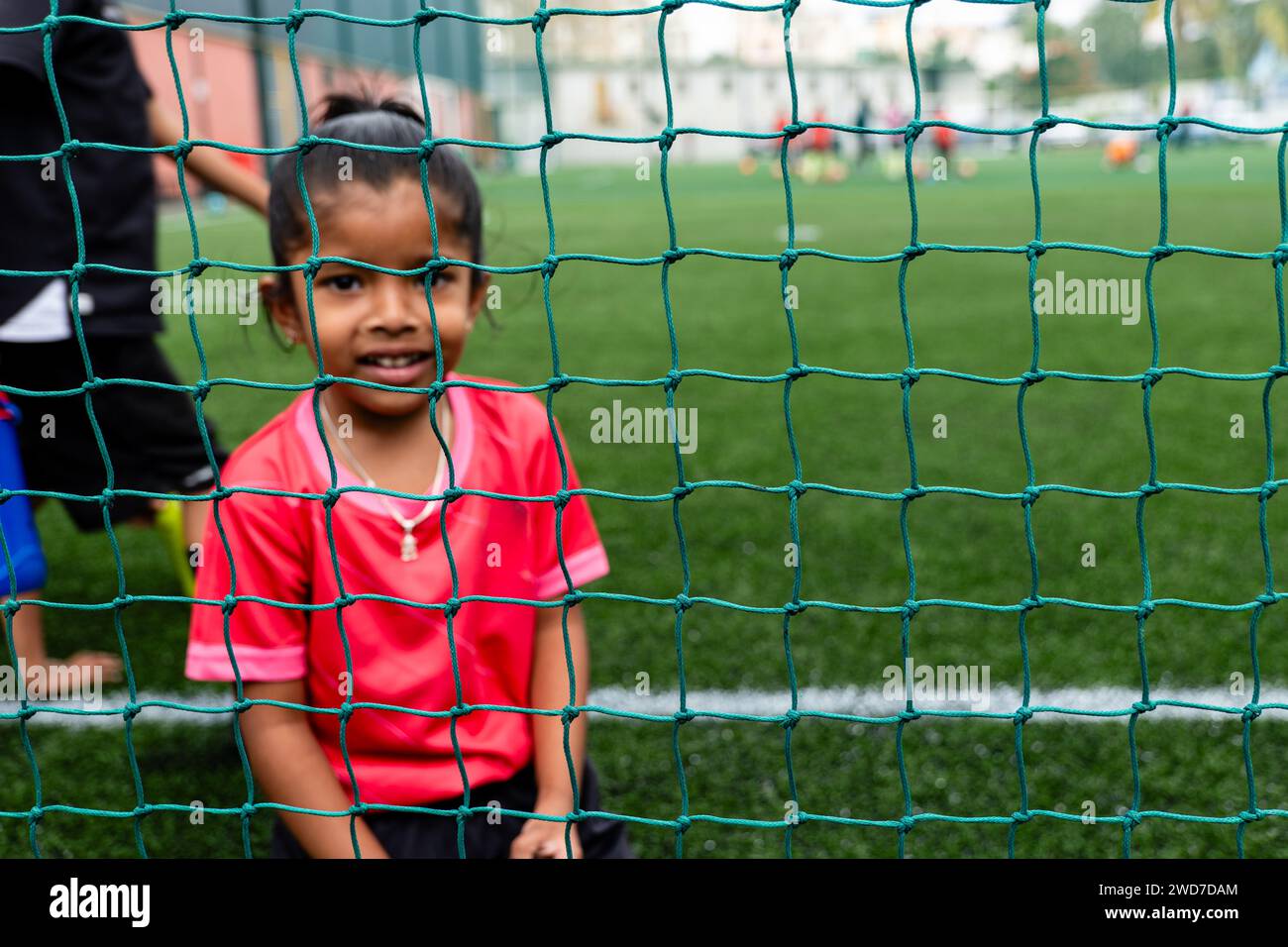 A young girl, eyes gleaming with determination, practices her football ...