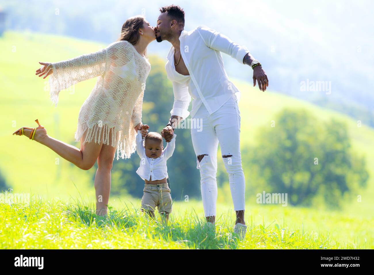 Multiethnic parents and mixed race baby walking on summer grass ...