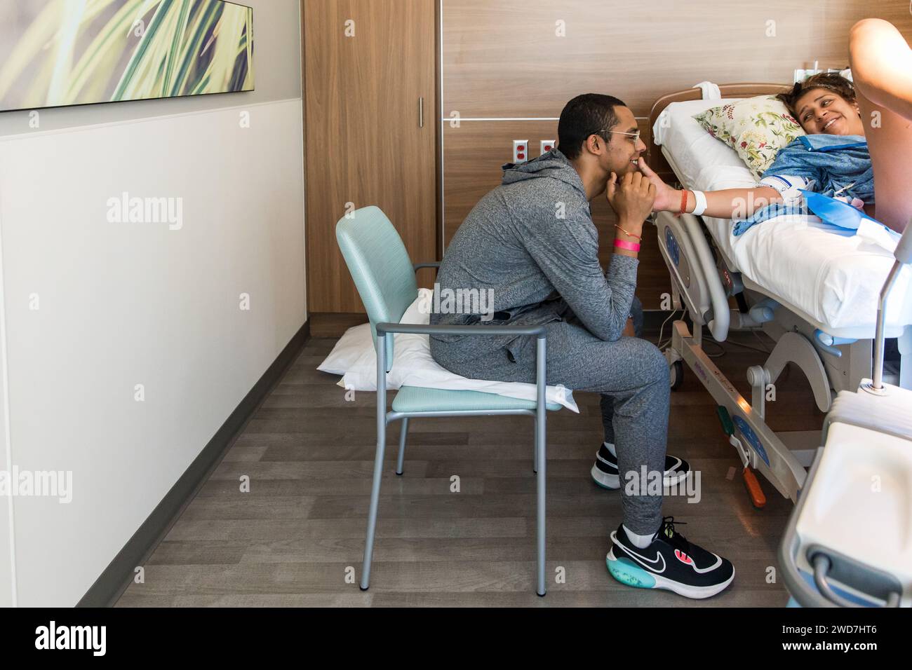 Multiracial couple holds hands and smiles during labor in hospital ...