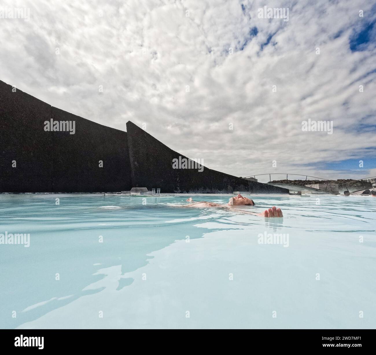 Man floats in hot springs pool under blue and clouds sky Stock Photo ...