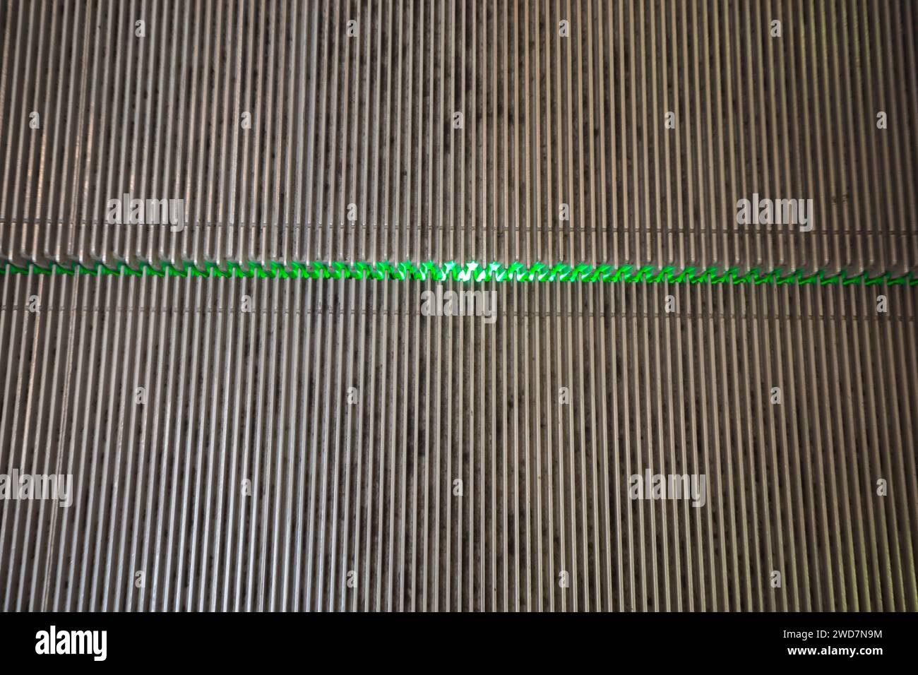 Bright green warning light alert shining through gap between steps to ...