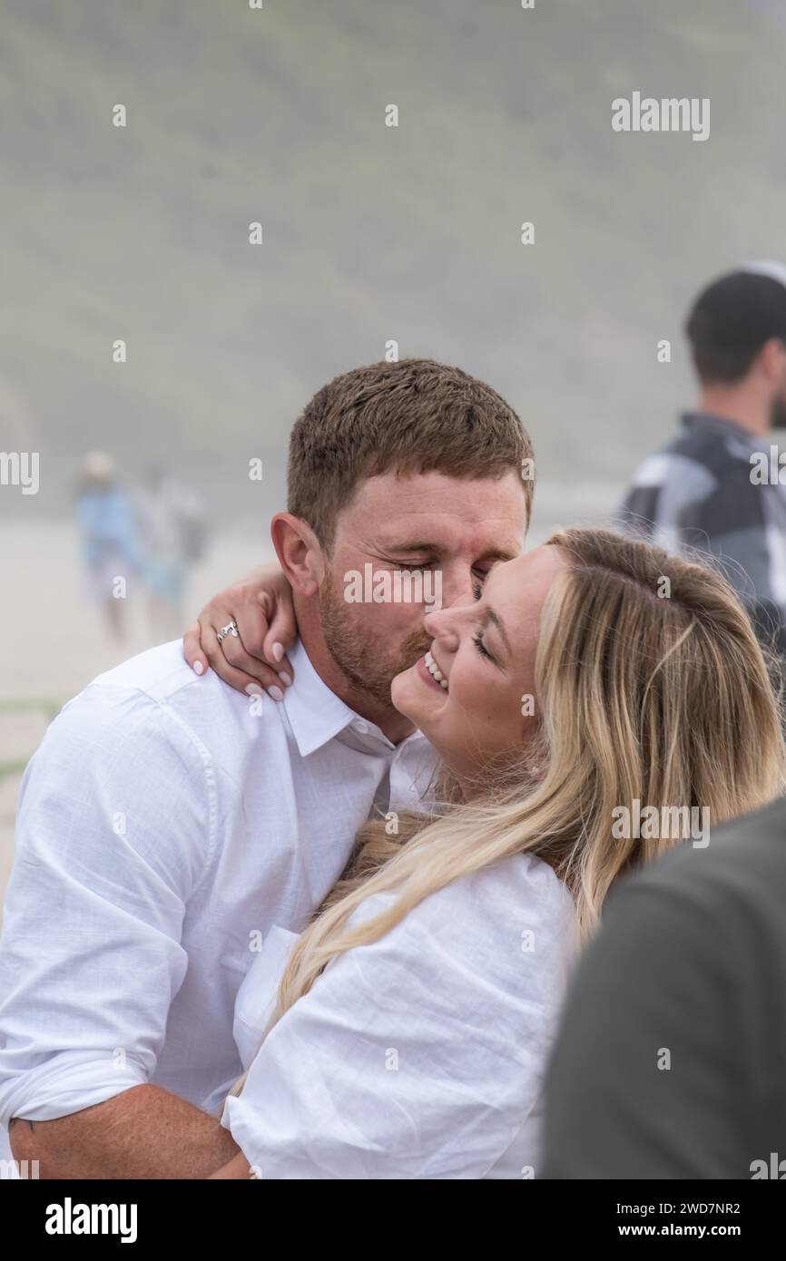 Romantic couple. Handsome husband embracing and kissing his beautiful wife with love. Young ...