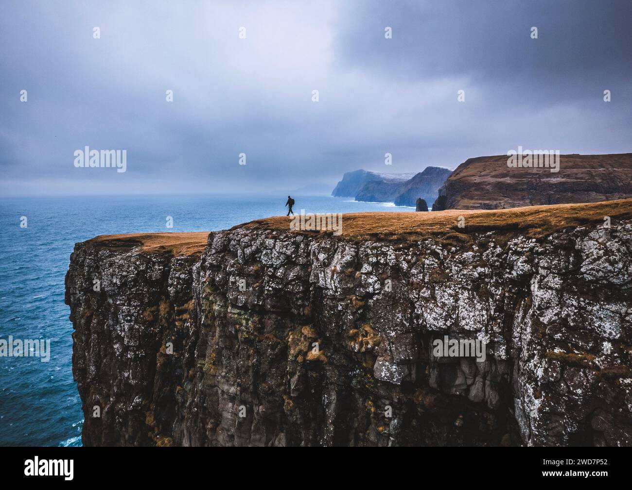 Hiker walks along edge of dramatic cliff in the Faroe Islands Stock ...