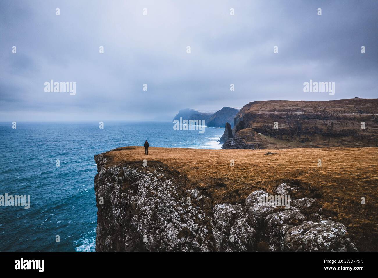 lone figure stands looking out over the ocean from top of cliff Stock ...
