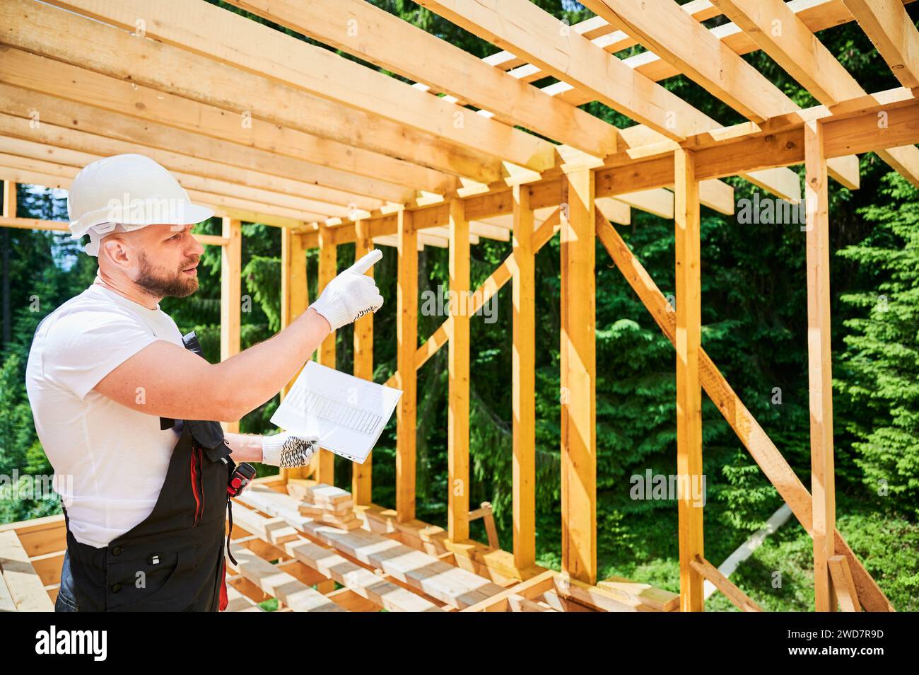 Surveyor inspecting construction plans of wooden two-story building ...