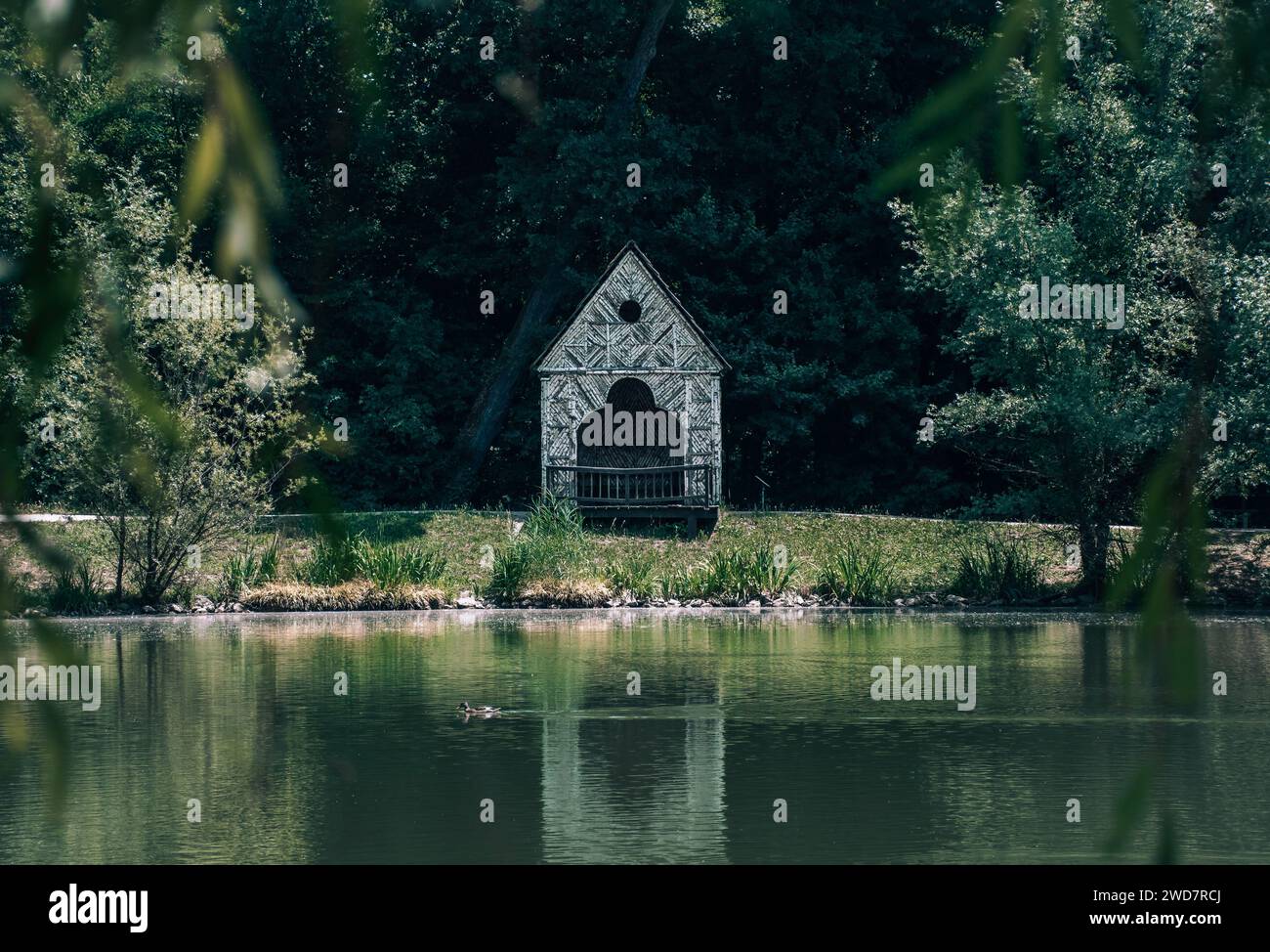 Picturesque wooden hut in the midst of lush greenery on lakeside at ...