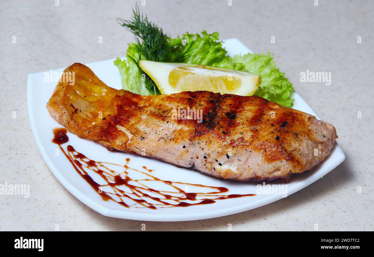 Grilled fried fish lies on a plate with lemon and herbs served in a ...