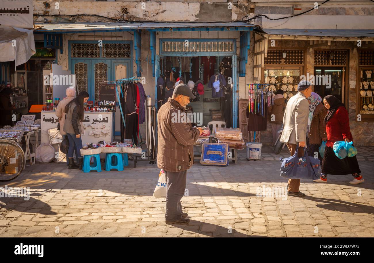 An elderly Tunisian man stops to look at his mobile phone in the souk ...