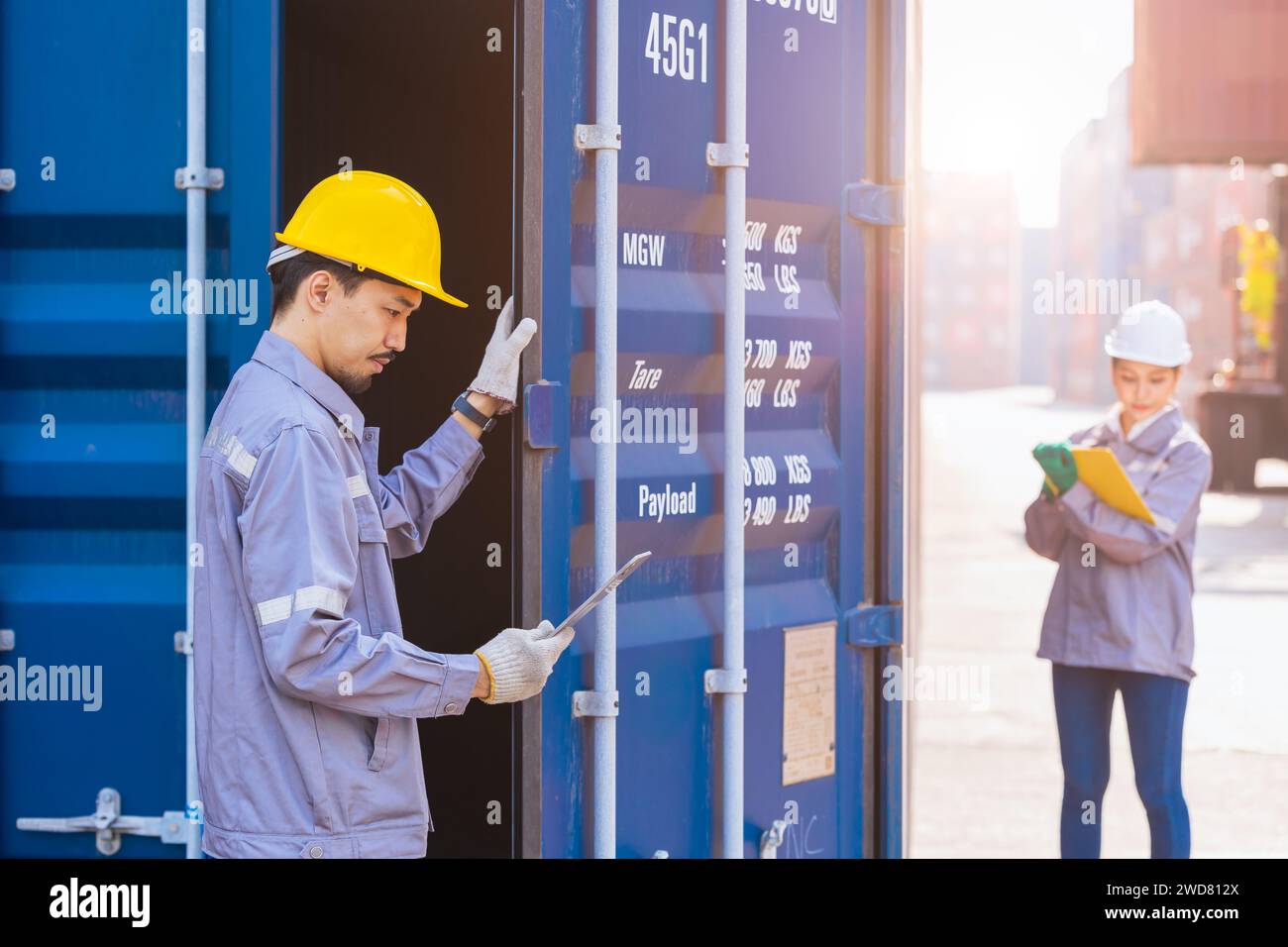 Asian man and women team workers customs staff teamwork in container yard port shipping cargo ...