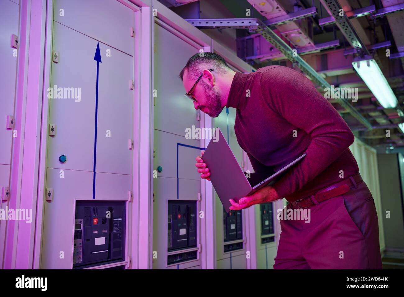 handsome focused data center specialist holding his laptop while ...