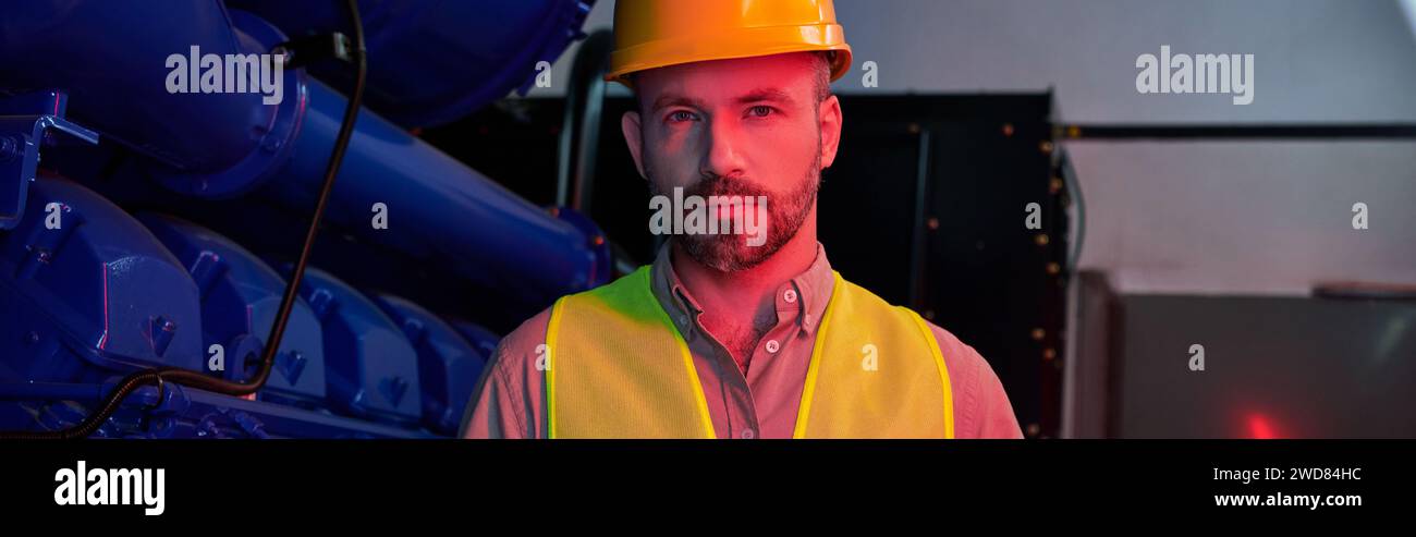 focused good looking technician with helmet and beard looking at camera ...