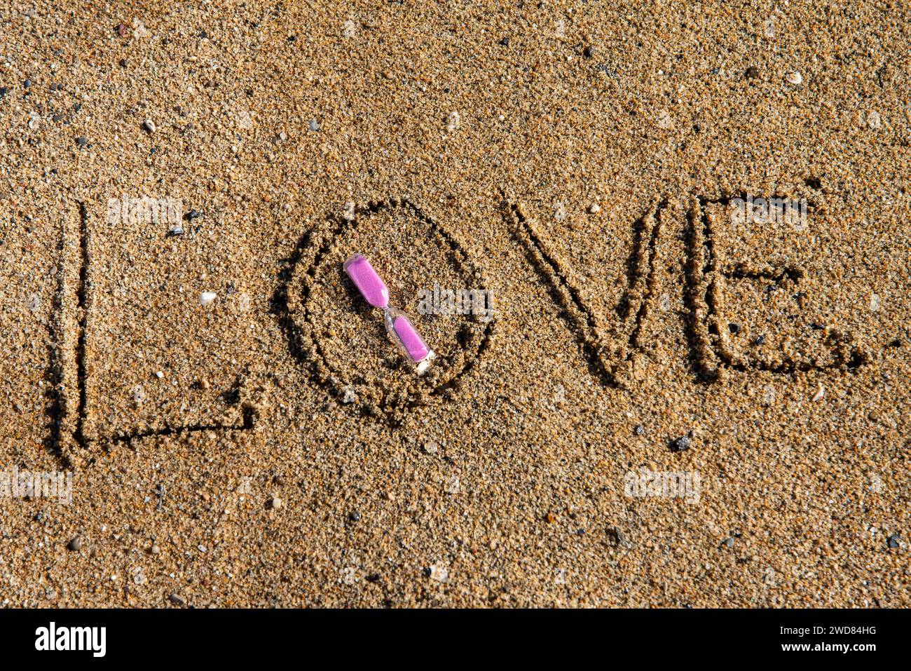 Timeless love: 'Love' inscribed on the beach, cradling a pink-hued ...