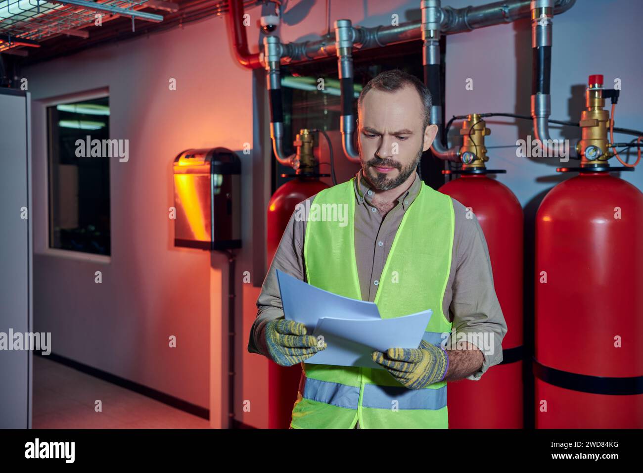 concentrated handsome technician looking attentively at his paperwork ...
