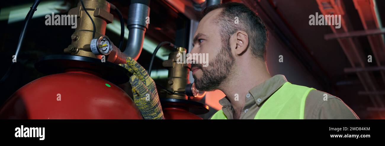 pensive technician in safety clothes checking gas cylinders during work ...
