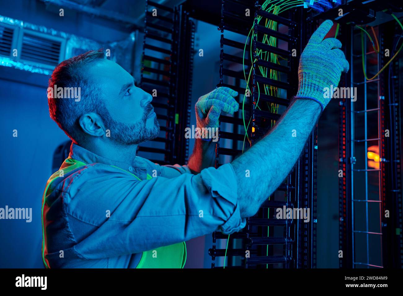 good looking concentrated technician in safety gloves and vest ...